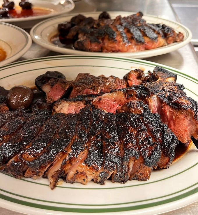 The porterhouse arrives like a meaty continent on a white plate, with a perfect medium-rare landscape that demands exploration.