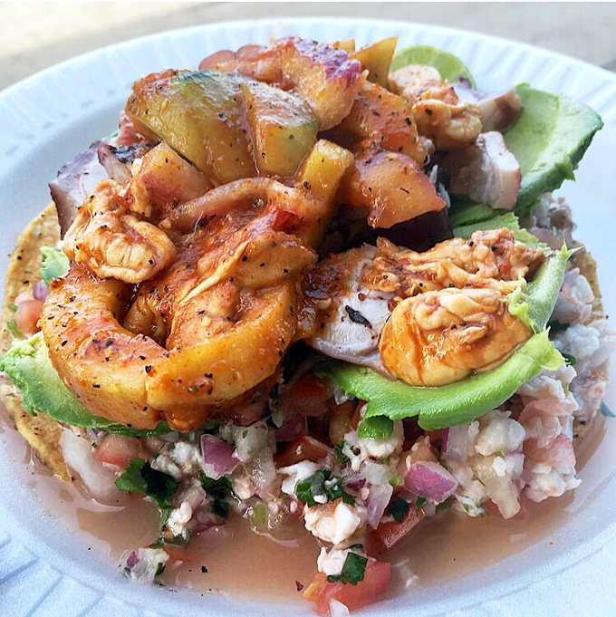 Seafood Jenga! This towering Poseidon tostada requires strategy to eat but rewards with layers of oceanic flavors in every precarious bite.