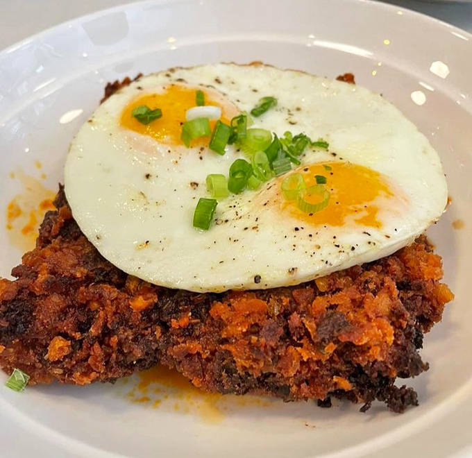 Breakfast nirvana achieved: crispy hash topped with perfectly sunny eggs. The scallion garnish adds the fresh pop that elevates this morning masterpiece.