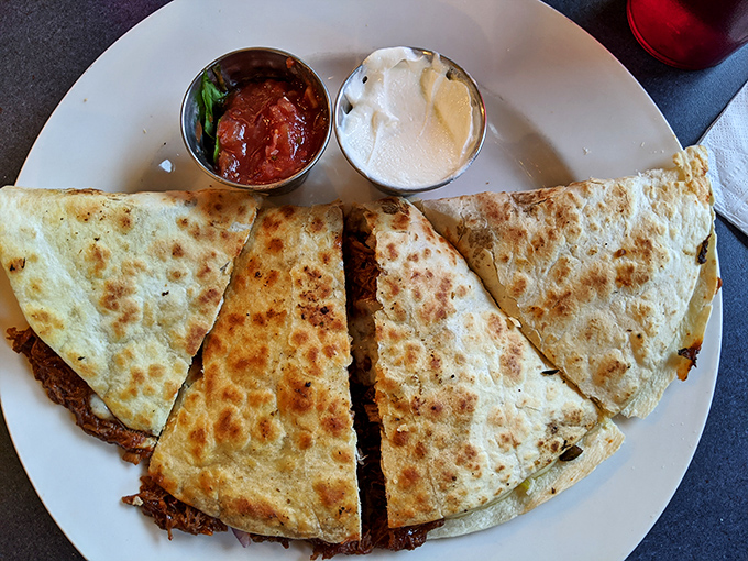 This quesadilla isn't messing around—golden-brown, stuffed to capacity, and served with the perfect ratio of salsa to sour cream.