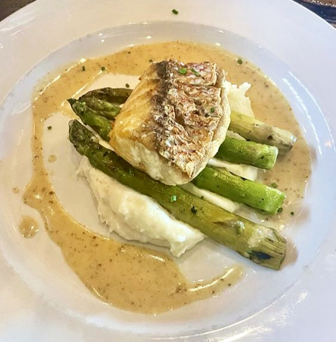 Red snapper lounging on asparagus spears like royalty on a throne. The sauce pools around it, creating a moat of buttery deliciousness.