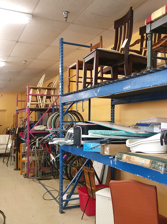 The furniture stacks reach toward the ceiling &ndash; chairs, bikes, and household miscellany forming a precarious sculpture of suburban life.