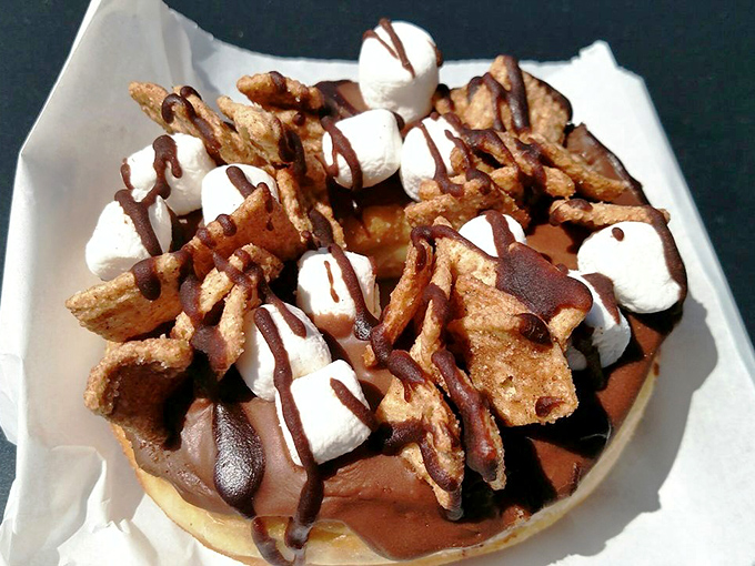 Campfire nostalgia meets donut innovation. This s'mores creation, topped with marshmallows, chocolate, and graham cracker pieces, proves donuts can absolutely be dinner.