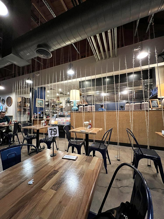 The exposed ductwork and rope dividers create an atmosphere that's both industrial chic and cozy breakfast nook.