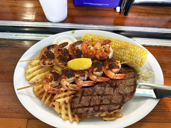 Land meets sea in perfect harmony &ndash; blackened shrimp skewers and a juicy steak sharing real estate with golden waffle fries.