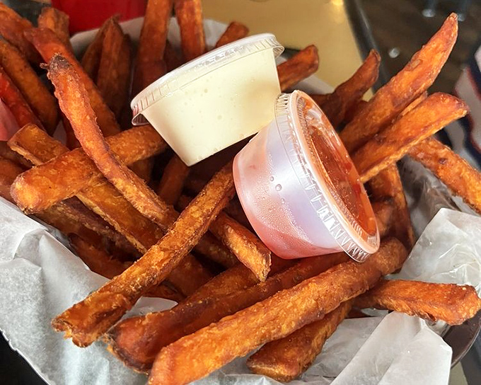 Sweet potato fries that achieve the impossible: crispy exterior, fluffy interior, and that perfect balance of sweet and savory that keeps your hand returning.