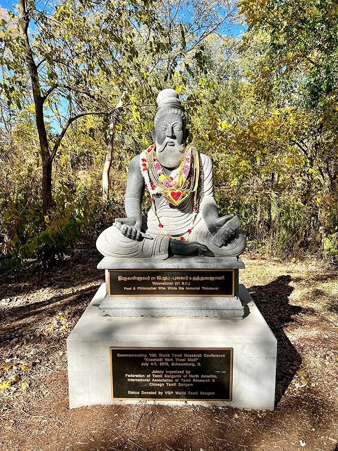 The statue of Thiruvalluvar brings Tamil cultural heritage to Illinois, adorned with colorful offerings from respectful visitors.
