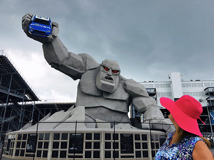 Hello down there! Miles surveys his domain with a bright blue race car souvenir, while a visitor in a vibrant hat captures the moment.