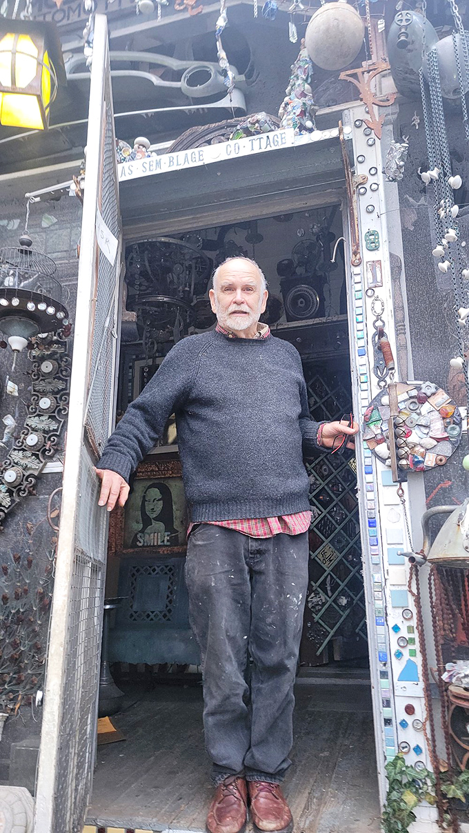 Standing in the doorway between conventional reality and artistic vision, the creator welcomes visitors to his metallic wonderland.