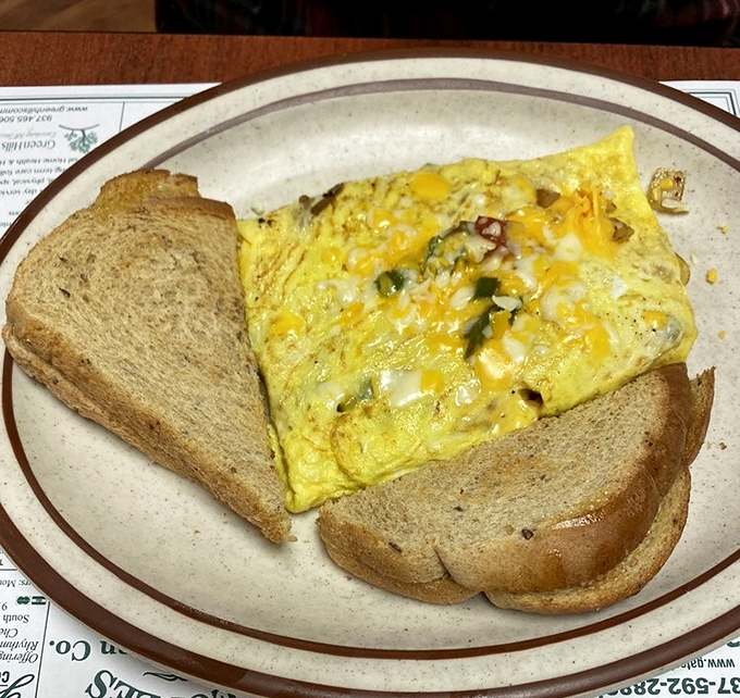 This isn't just breakfast—it's a fluffy yellow canvas of eggs studded with vegetables and cheese, with toast standing by for dipping duty.