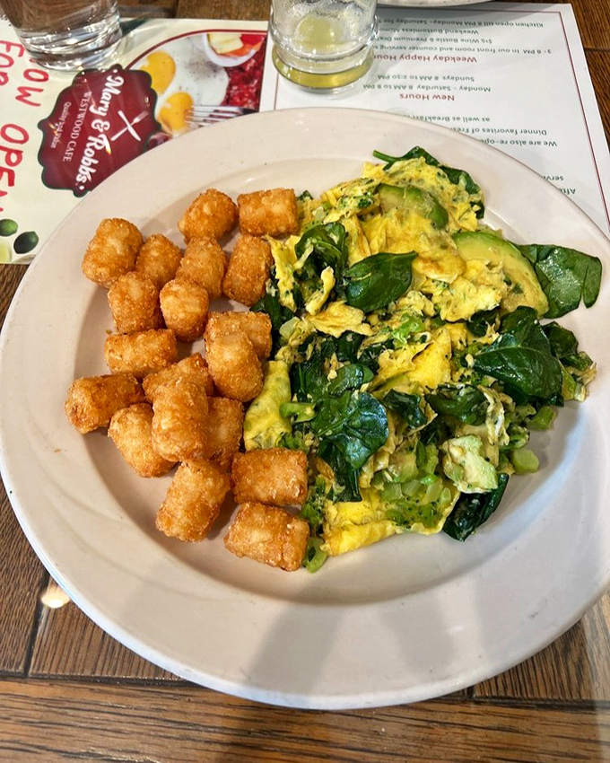 A scramble that's having a love affair with spinach and avocado, while the tater tots stand by, golden and ready for their moment.