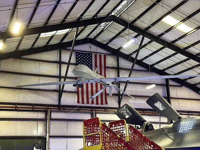 Modern unmanned aircraft hang beneath Old Glory, illustrating how aviation has evolved from daredevil pilots to remote operators and artificial intelligence.