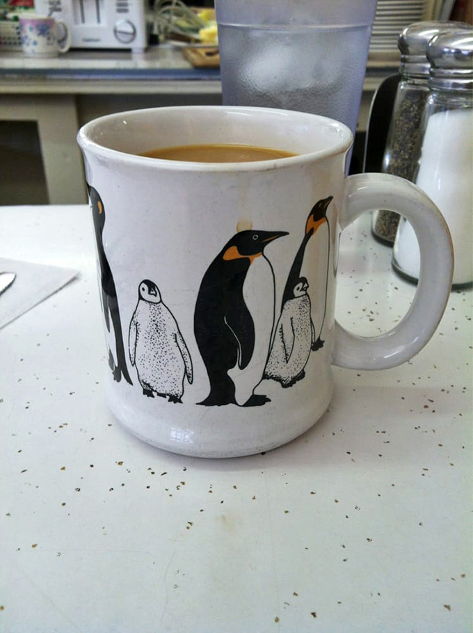 Your coffee arrives in whatever mug was next in line&mdash;this one featuring penguins who seem equally delighted about the morning caffeine situation.
