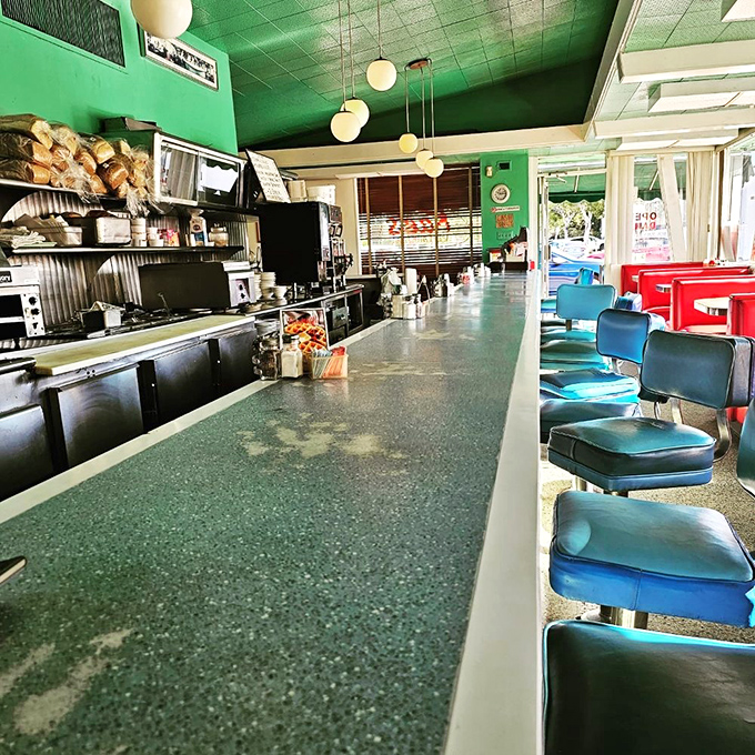 The counter stretches like a blue vinyl runway, each stool a front-row seat to the greatest show on earth: breakfast being made.