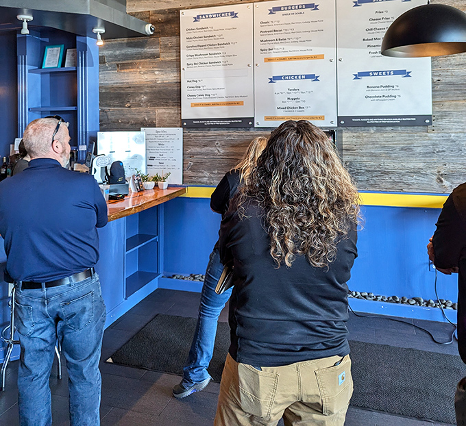 The menu board attracts customers like a burger-scented magnet&mdash;notice how everyone's already deciding before they even reach the counter?