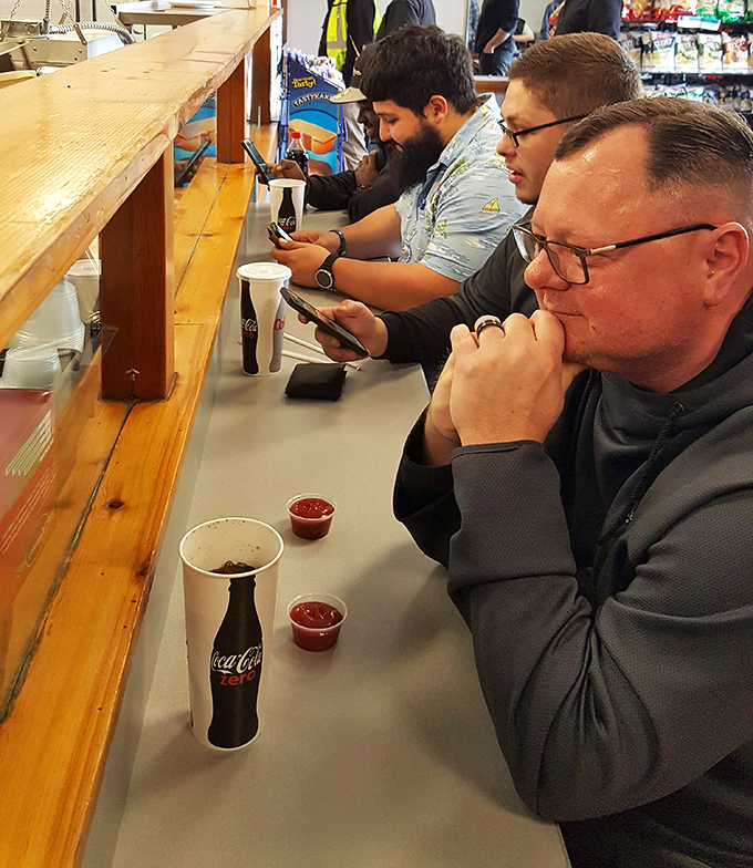 The counter where decisions are made and anticipation builds. These gentlemen know they're moments away from sandwich satisfaction.