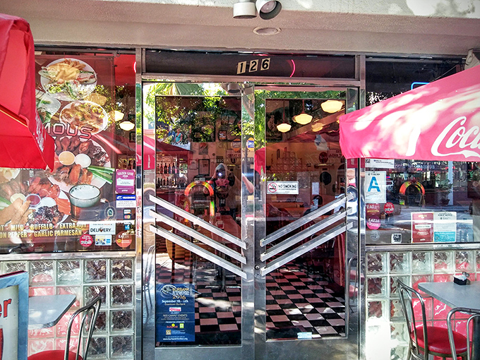 The entrance doors feature classic mid-century chevron design. Glass blocks and neon signage announce you're leaving 2023 behind as you step inside.