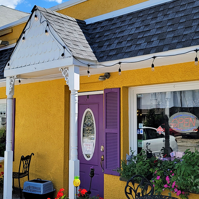 That purple door isn't just an entrance &ndash; it's a portal to comfort food paradise, framed by cheerful flowers and charming architectural details.