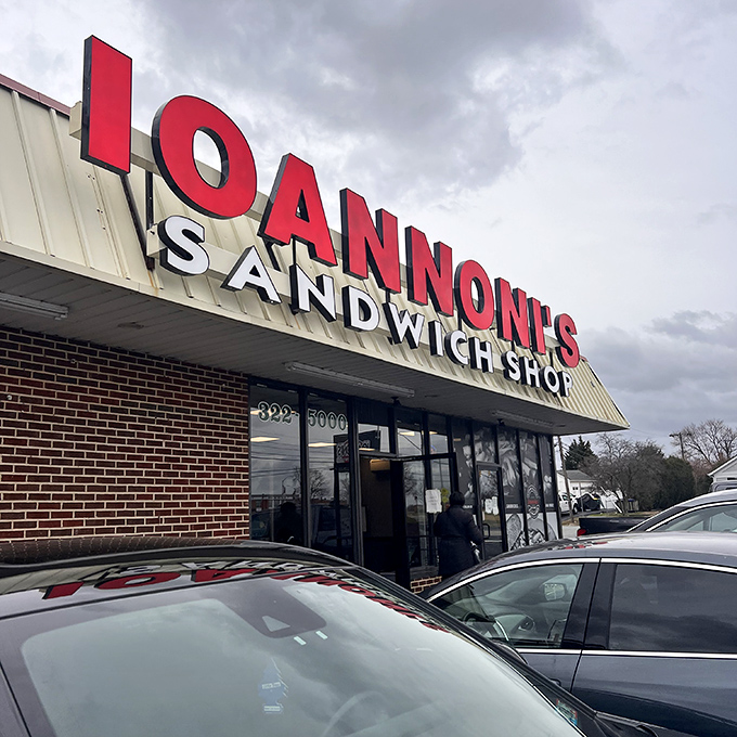 Even on cloudy days, that red signage shines like a lighthouse guiding hungry travelers to sandwich salvation.