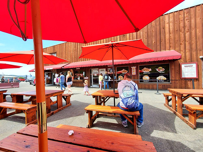 Red umbrellas and wooden picnic tables create the perfect stage for seafood theater, where the Pacific Ocean provides both the backdrop and the main ingredients.