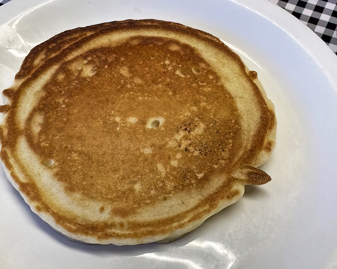 The humble pancake, elevated to art form. Golden-brown, perfectly round, and ready for its maple syrup baptism.