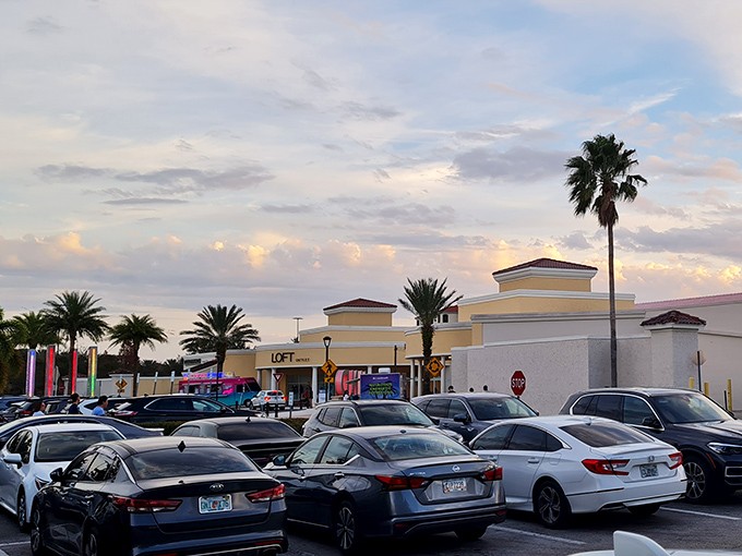 As dusk settles over the parking lot, cars rest like tired shoppers, their trunks filled with the day's conquests.