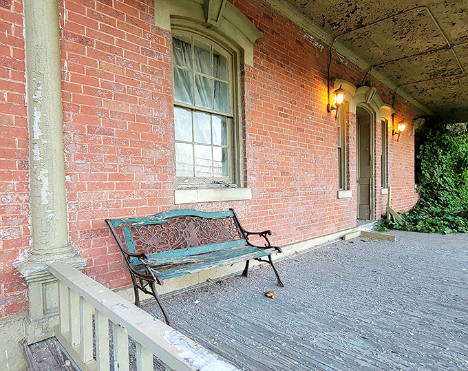 The weathered porch bench invites visitors to sit and contemplate the boundary between the infirmary's imposing interior and the freedom just beyond.