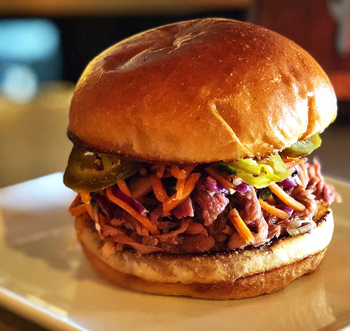 This isn't just a sandwich; it's an architectural marvel of tender pulled pork, crunchy slaw, and pickles on a perfectly toasted brioche throne.