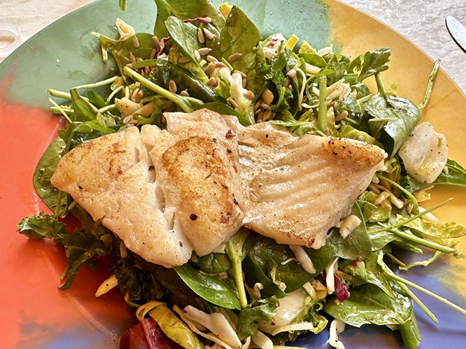 Fish taking a spa day on a bed of greens. This delicate white fillet, perfectly seared and resting on a vibrant salad, offers a lighter option that doesn't sacrifice flavor.