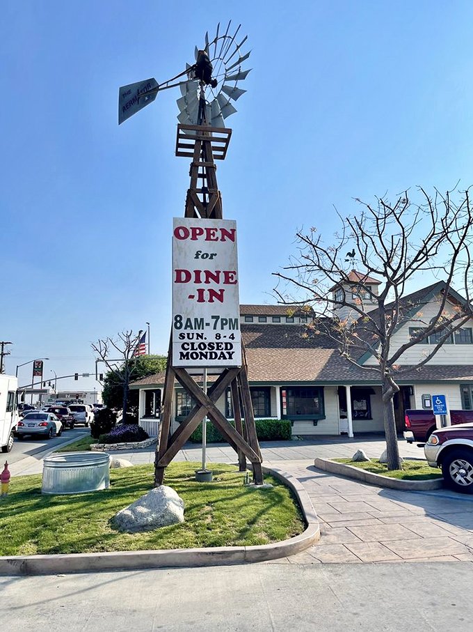 The windmill sign stands tall like a quirky lighthouse, guiding hungry travelers to safe harbor with its promise of "OPEN for DINE-IN" salvation.