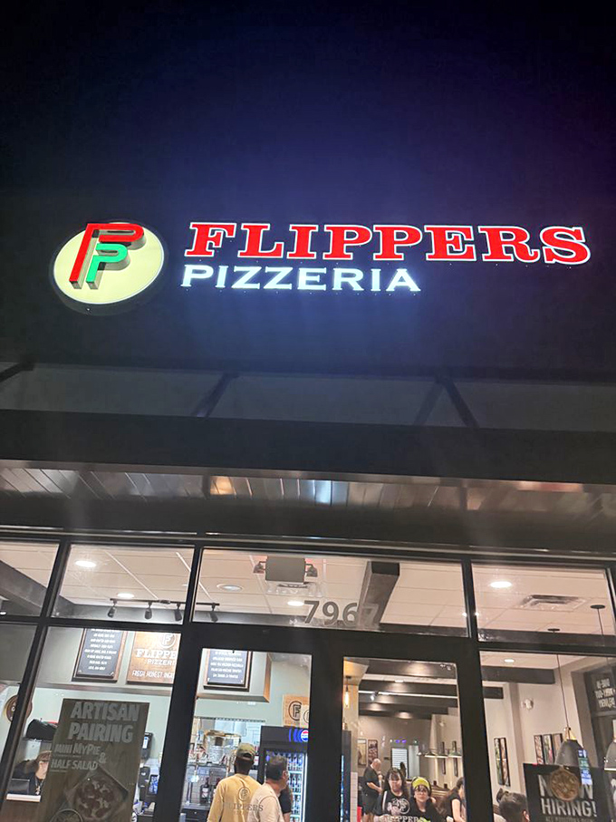 The Flippers sign glows like a pizza lighthouse, guiding hungry travelers safely to shore after a day of theme park adventures.