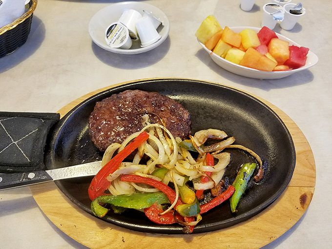 A sizzling steak performance with a supporting cast of peppers and onions. The fruit cup watches from the sidelines, offering balance.