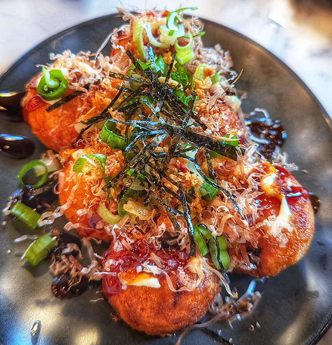 Takoyaki balls topped with dancing bonito flakes &ndash; like tiny octopus-filled planets orbiting your plate.