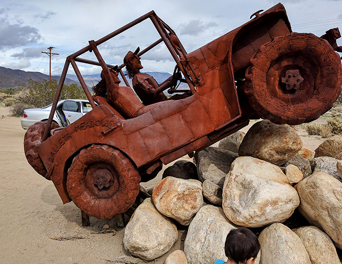 Off-roading through time! This vintage Jeep sculpture climbs an eternal hill, its metal passengers forever enjoying the thrill of desert exploration.