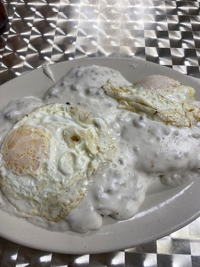Eggs swimming in creamy sausage gravy&mdash;where breakfast meets art in a plate-sized canvas of delicious comfort.
