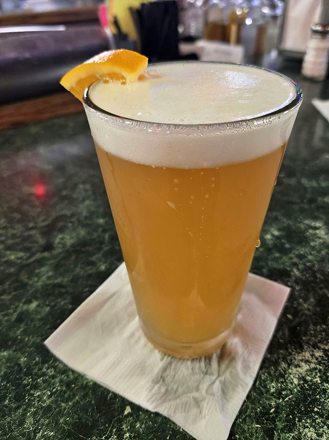 A perfectly poured beer with an orange slice perched on the rim &ndash; because sometimes the desert heat demands nothing less than golden, effervescent refreshment.