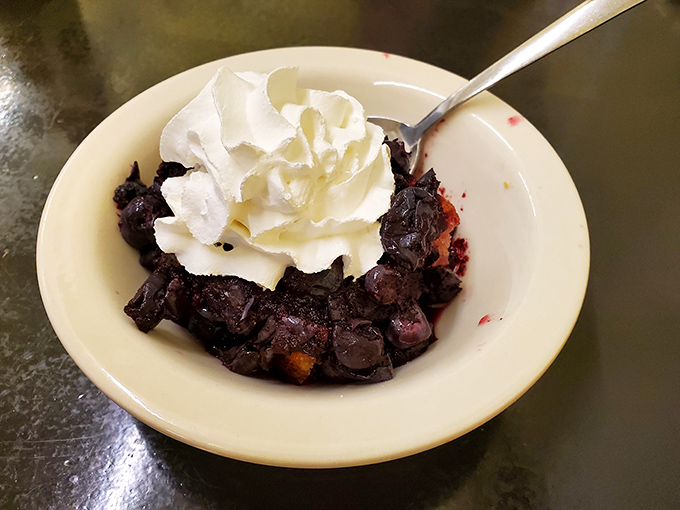 A bowl of blueberry cobbler topped with a cloud of whipped cream&mdash;proof that saving room for dessert is always the right decision.
