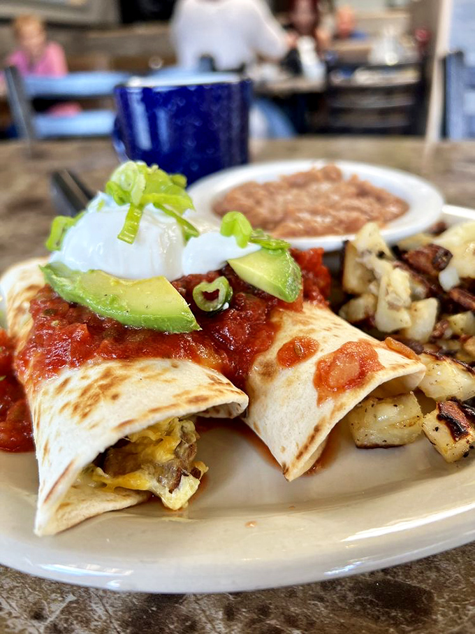 Breakfast burritos topped with avocado and salsa—California's contribution to morning happiness, served with a side of potatoes.