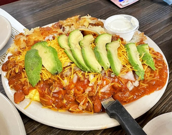 An omelet that's having an identity crisis as chili, topped with avocado slices like green smiles. California breakfast fusion at its most magnificent.