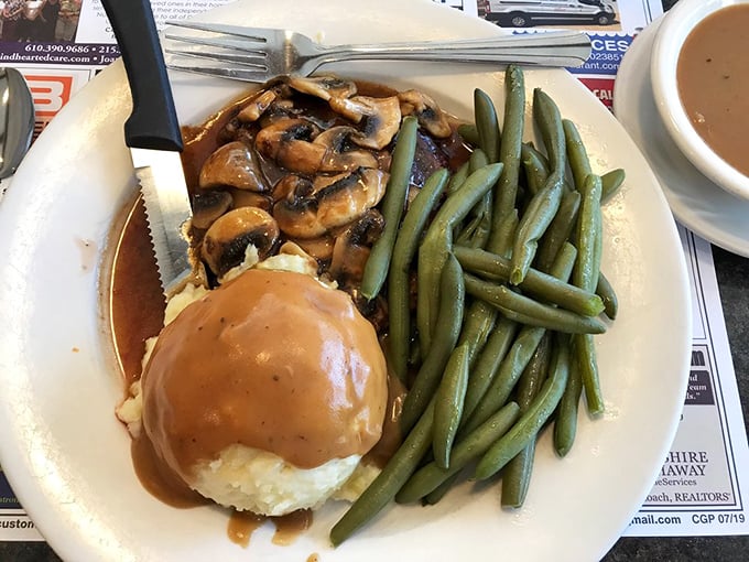 A plate of salisbury steak swimming in mushroom gravy&mdash;the kind of meal that makes you want to hug the chef afterward.
