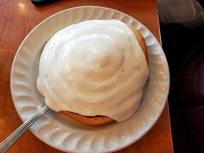 This isn't just a cinnamon roll—it's a spiral-shaped monument to indulgence, wearing its cream cheese frosting like a royal robe.