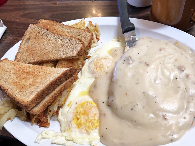 Country fried steak swimming in gravy with eggs standing by. This plate doesn't just feed you&mdash;it hugs your soul from the inside.