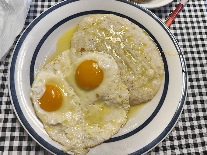 Sunny-side up eggs nestled against creamy grits—the breakfast equivalent of a warm hug. Southern comfort on a blue-rimmed plate.