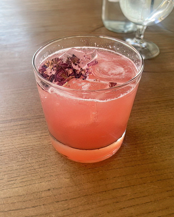 A rosy cocktail garnished with dried flowers captures the essence of sophisticated refreshment. The perfect companion for people-watching or between-course conversation.