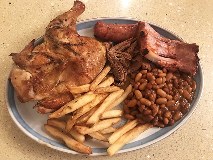 BBQ's greatest hits on a single plate—smoky chicken, tender pulled pork, and those beans that have clearly been simmering with purpose. The fries are just showing off.