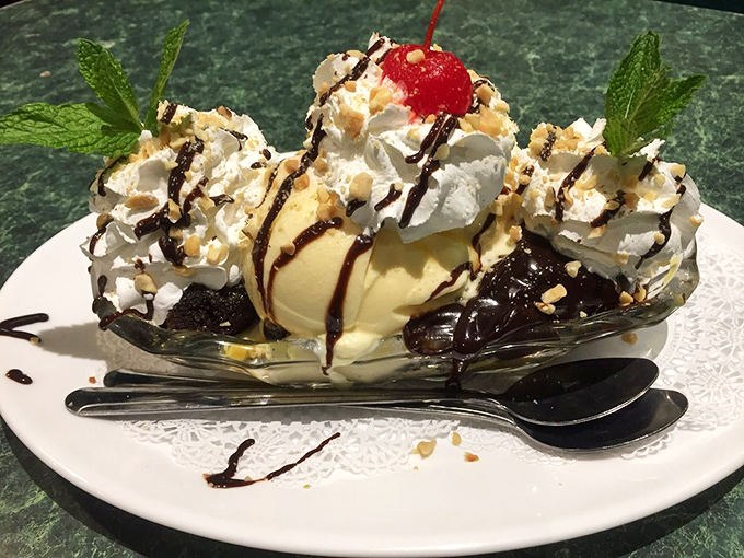 A hot fudge sundae that demands to be photographed. Vanilla ice cream, whipped cream mountains, chocolate drizzle, and that cherry on top&mdash;dessert architecture at its finest.