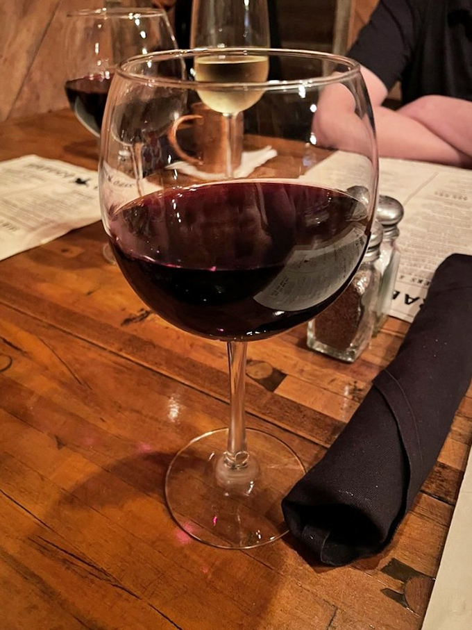 Wine in proper glassware on a rustic wooden table. Because even in a place that cuts ties, some traditions are worth keeping.