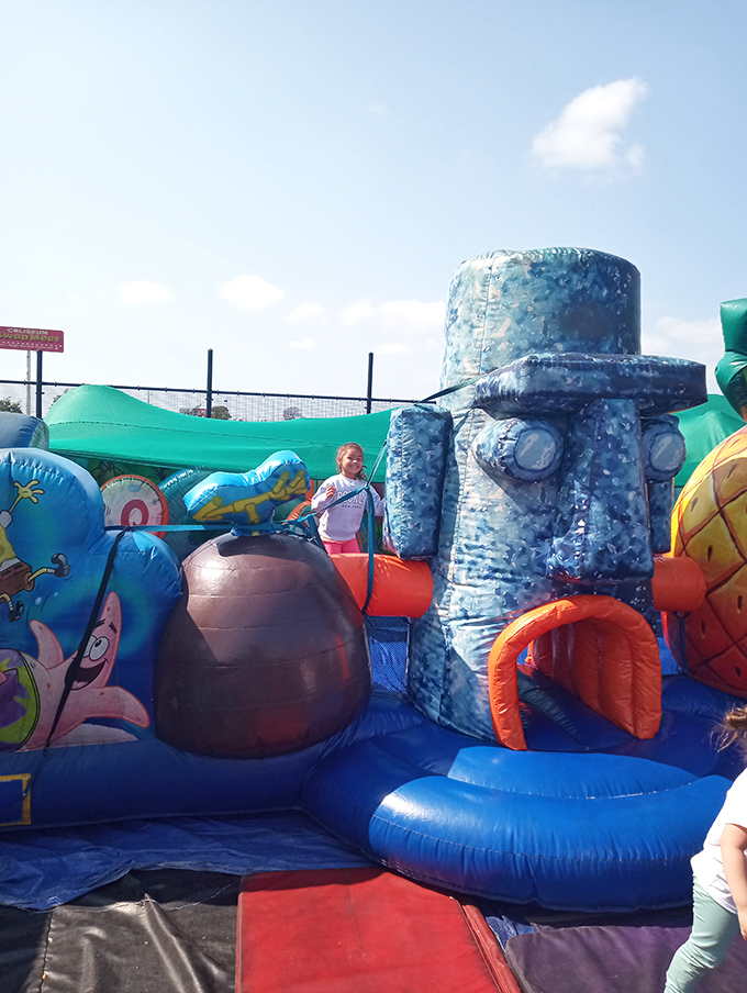 Childhood joy takes inflatable form in a bounce house kingdom where kids burn energy while parents hunt for bargains nearby.