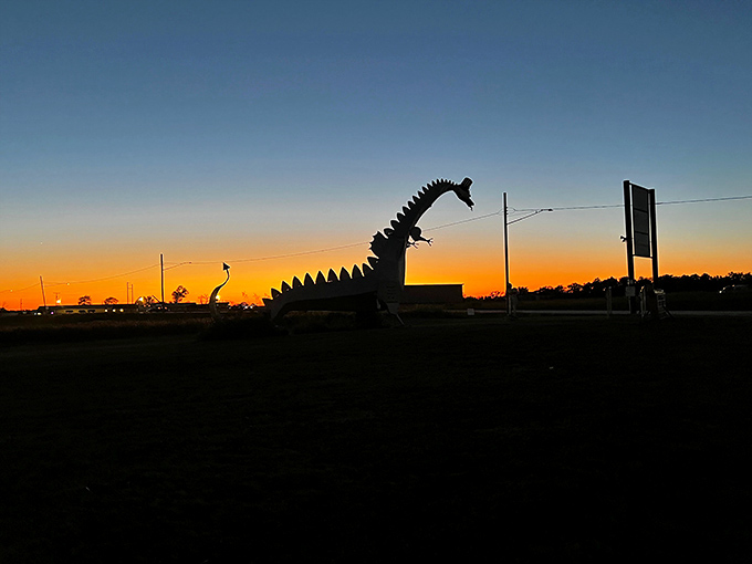 As sunset paints the sky, the dragon's silhouette creates pure roadside poetry against the endless Illinois horizon.