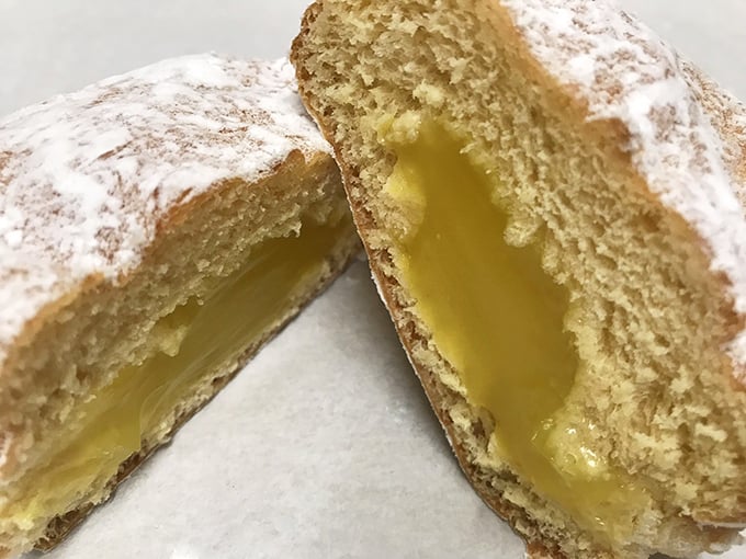The lemon-filled powdered donut reveals its secret—a bright, tangy center that balances the sweetness with a perfect citrus punch.